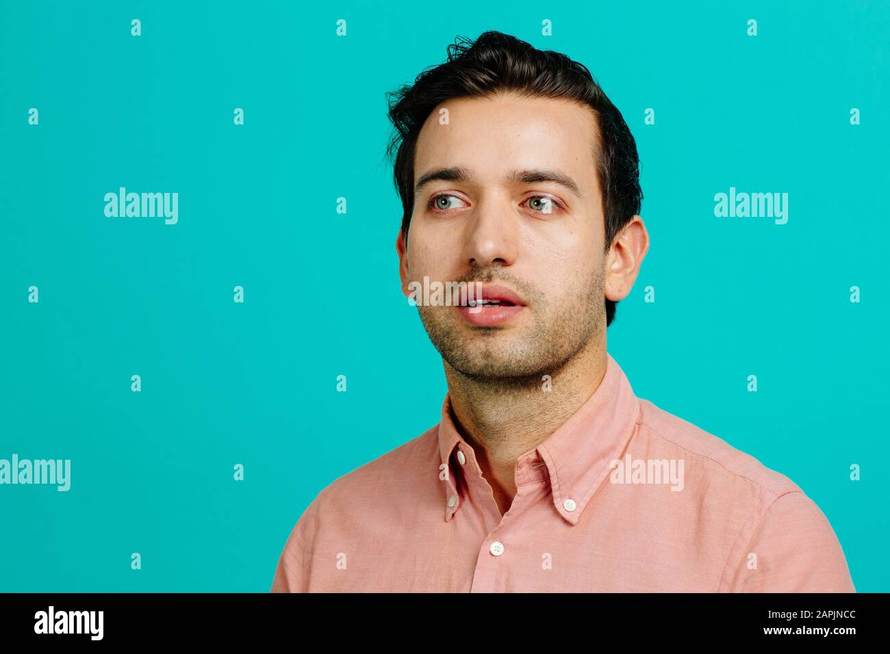 Portrait of a young adult man smiling, isolated on blue studio ...