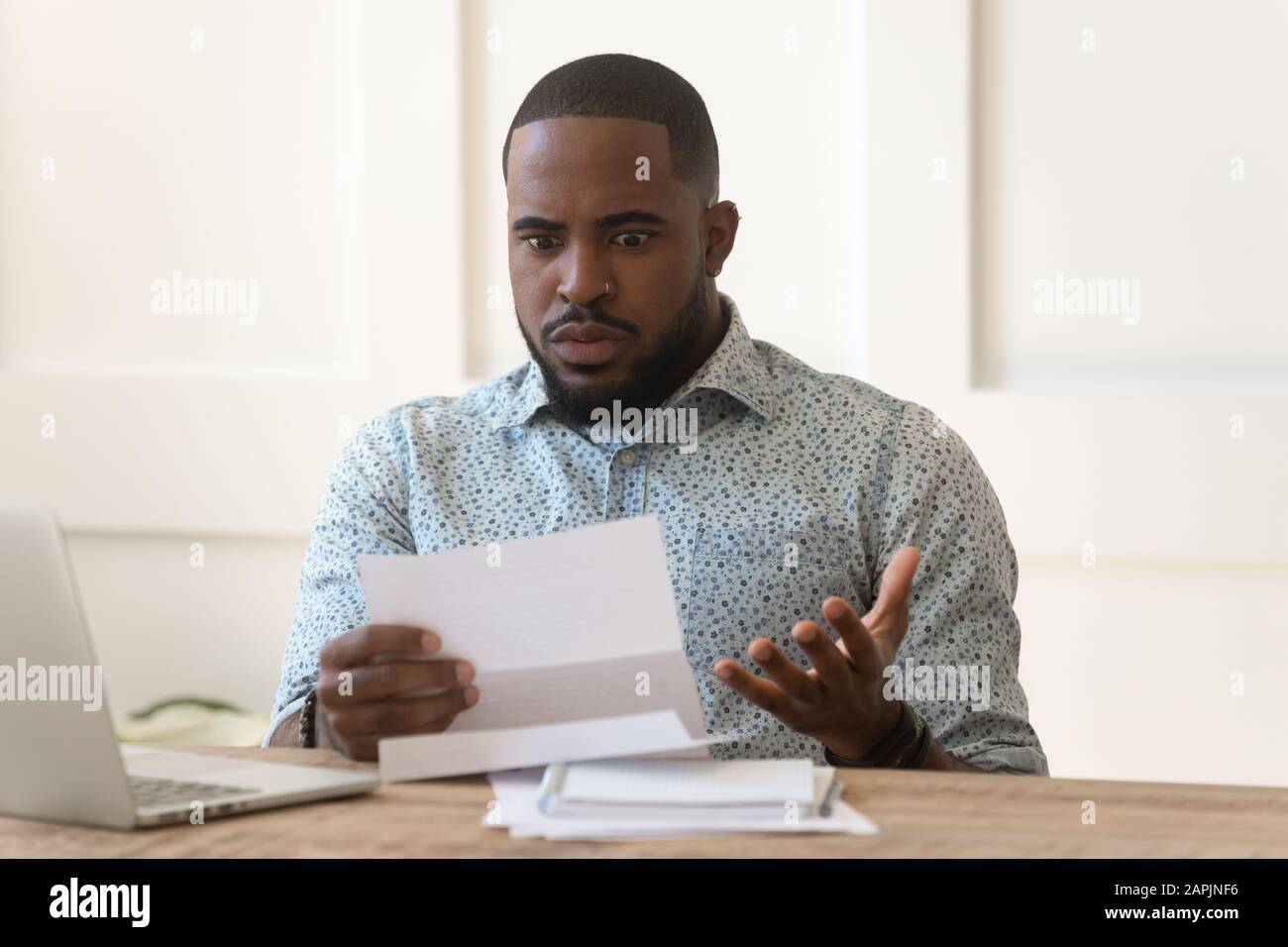 Confused african man holding mail letter reading shocking unexpected ...