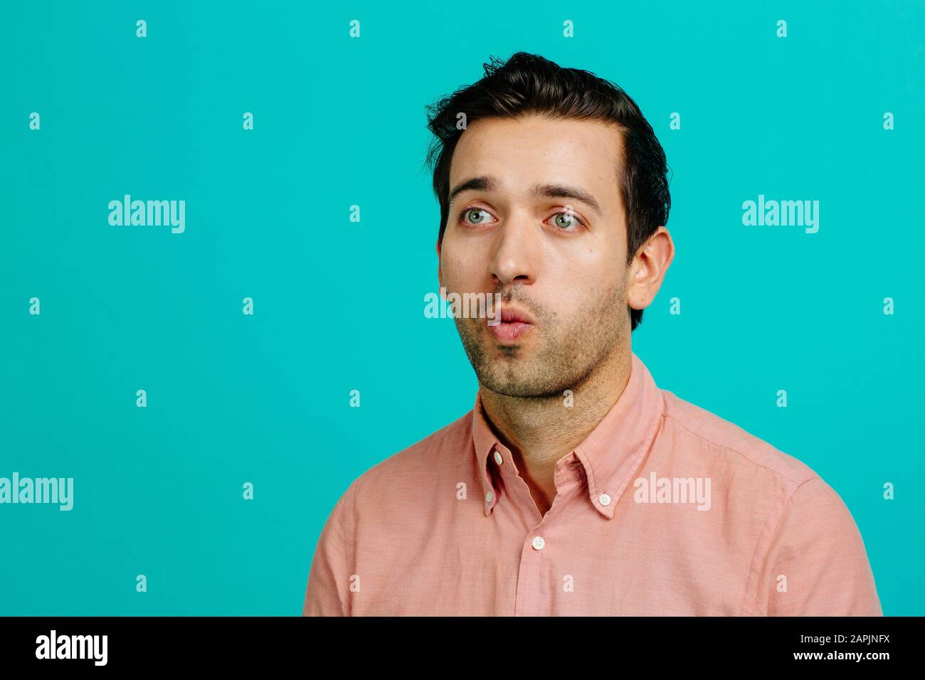 Portrait of a young adult man making funny faces, isolated on blue ...