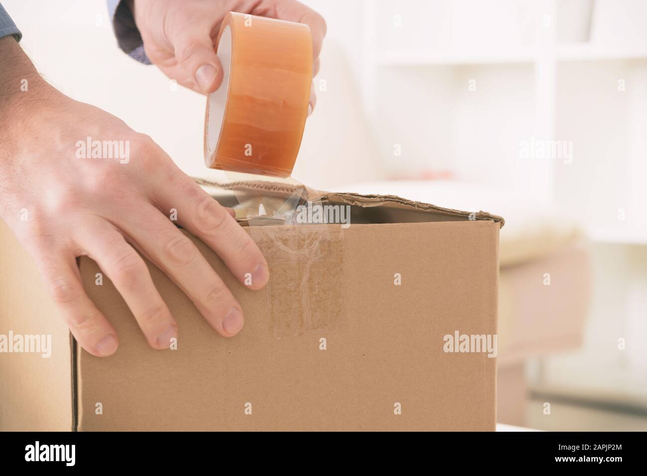 Hand holding the adhesive tape and taping the cardboard box Stock Photo ...