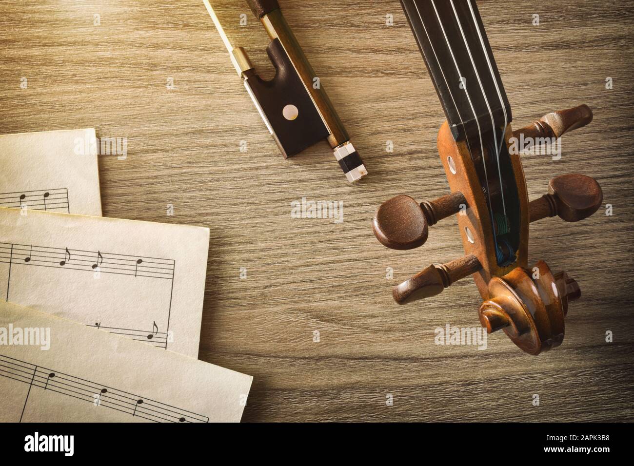 Violin pegbox and bow with sheet music on wood table vintage. Top view ...
