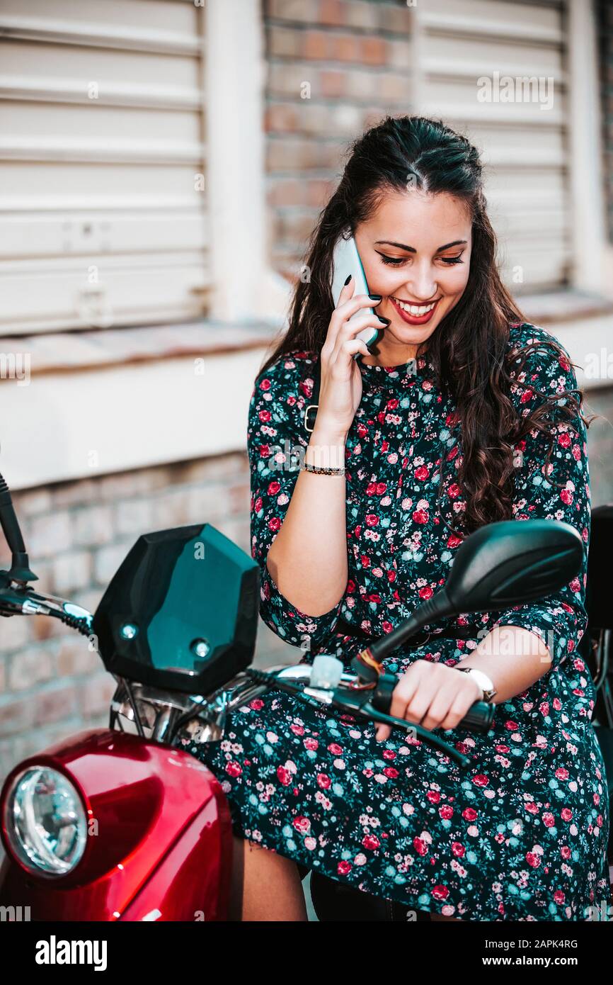 Happy cheerful young woman talking on the phone in the street, smiling ...