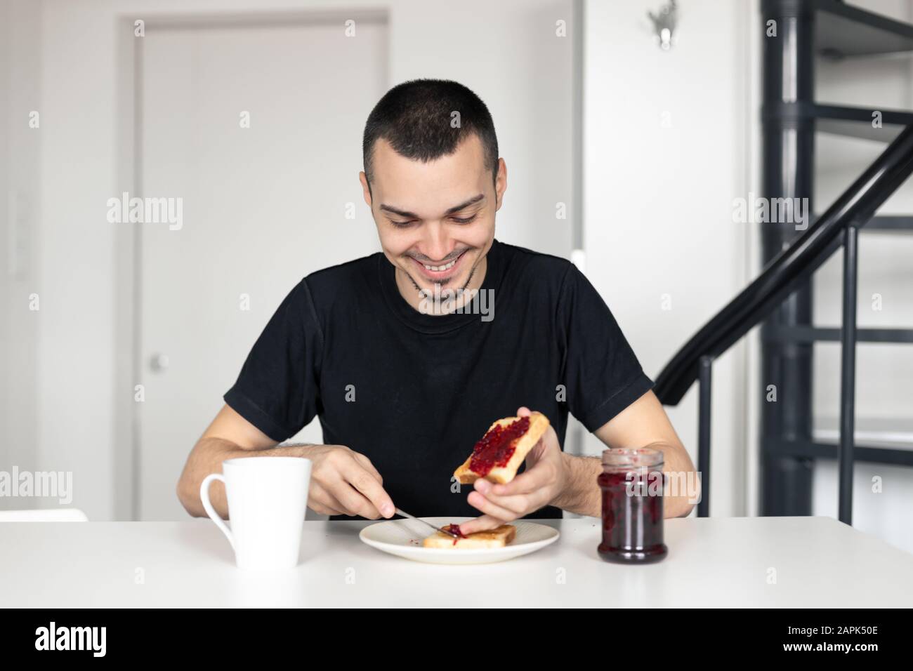 The guy has breakfast with toast with jam Stock Photo - Alamy