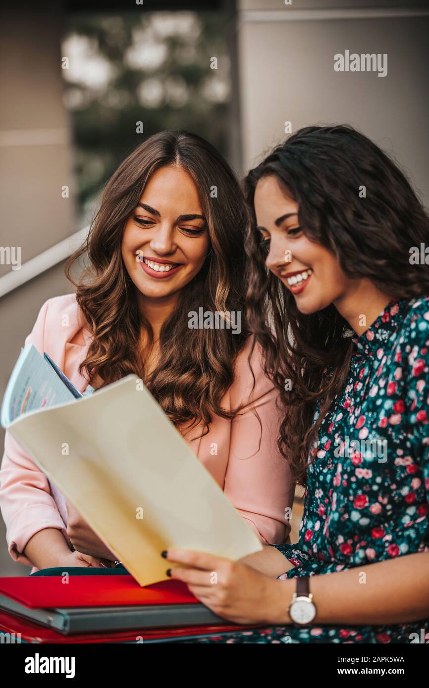 Two beautiful female friends, students checking paper notes before exam ...