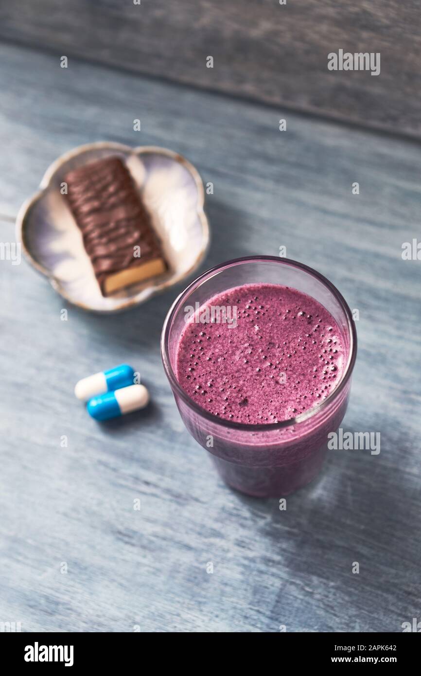 Glass of Protein Shake with milk and blueberries, Creatine capsules and ...