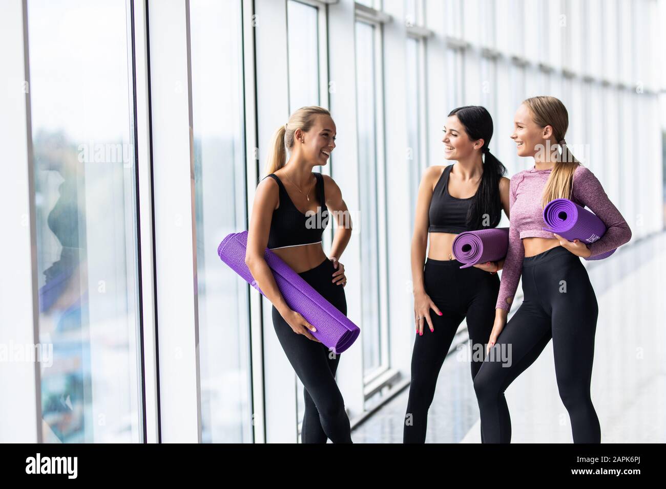 Group of young sporty girls with yoga mats standing at gym. Female ...