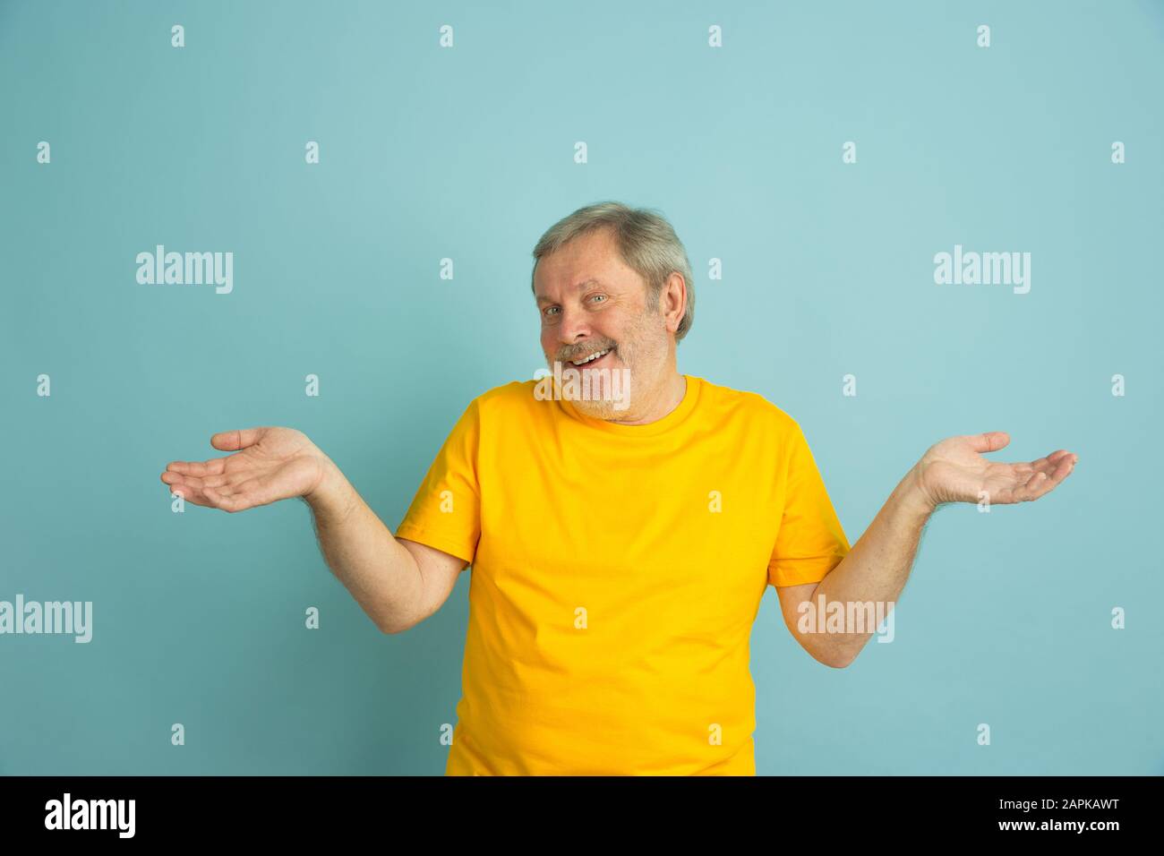 Inviting, uncertain gesture. Caucasian man portrait isolated on blue ...