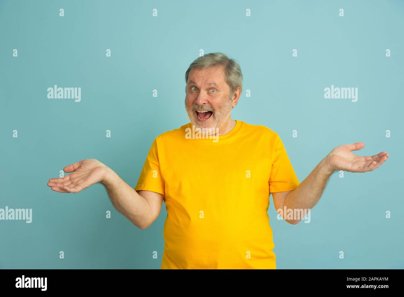 Inviting, uncertain gesture. Caucasian man portrait isolated on blue ...