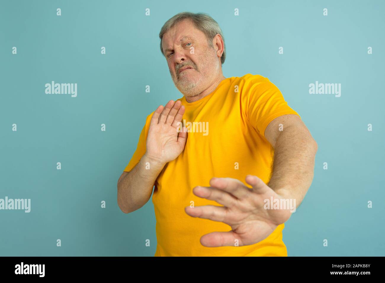 Scared, rejecting. Caucasian man portrait isolated on blue studio ...