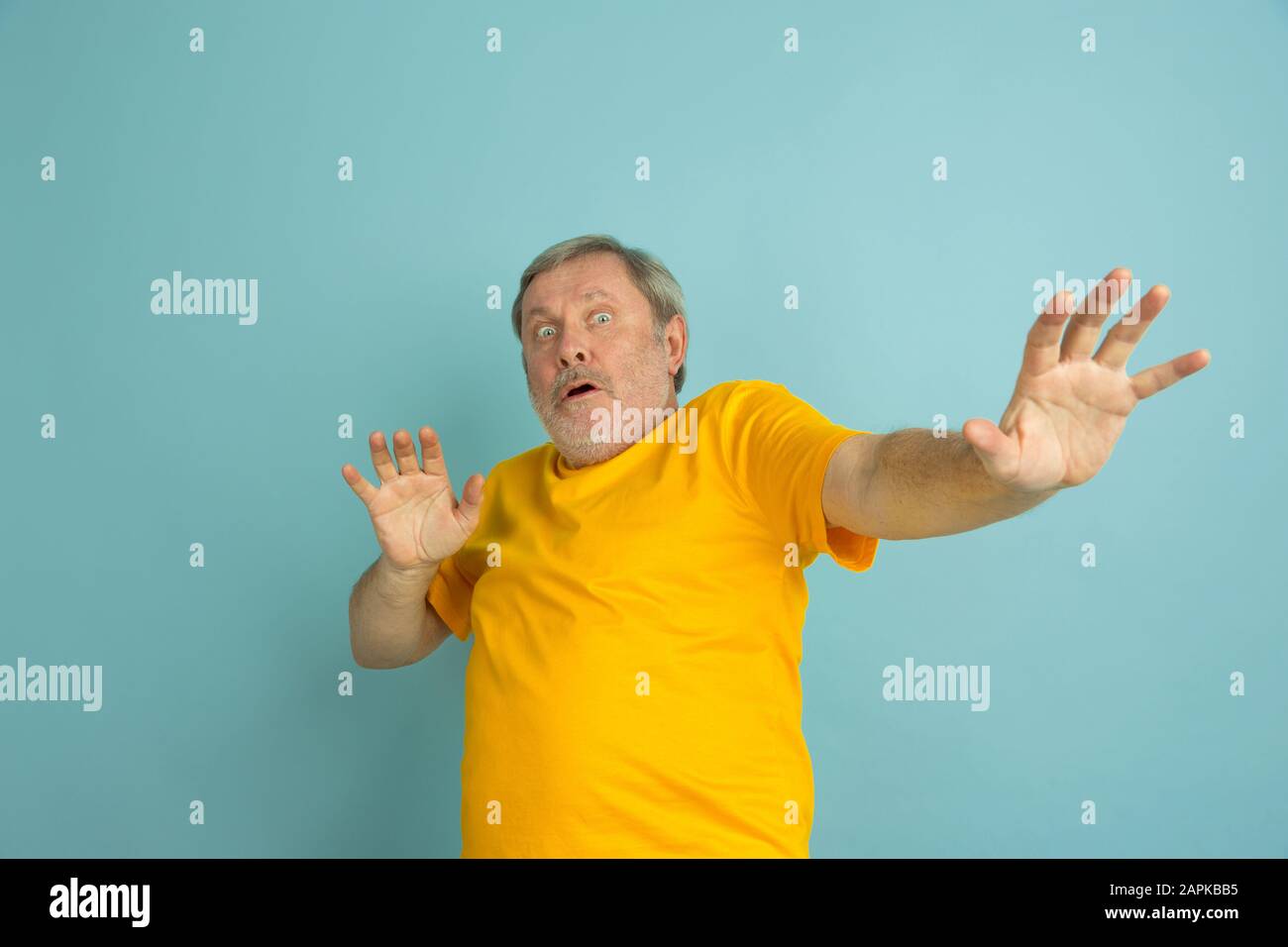 Scared, rejecting. Caucasian man portrait isolated on blue studio ...