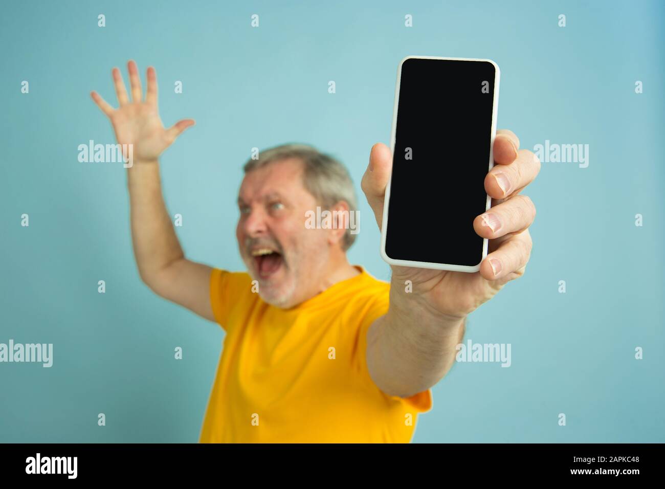 Showing phone's blank screen, winner. Caucasian man portrait on blue ...