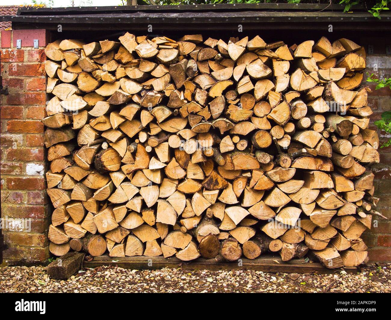 A neat pile of stacked cut logs of wood waiting to be used as fuel in a ...