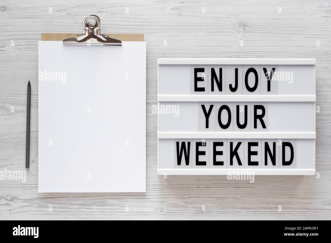 'Enjoy your weekend' words on a lightbox, clipboard with blank sheet of ...