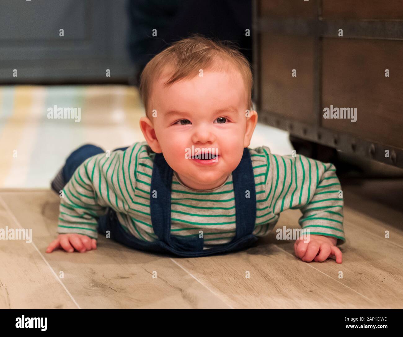 Seven month old baby boy happily crawling across living room floor ...
