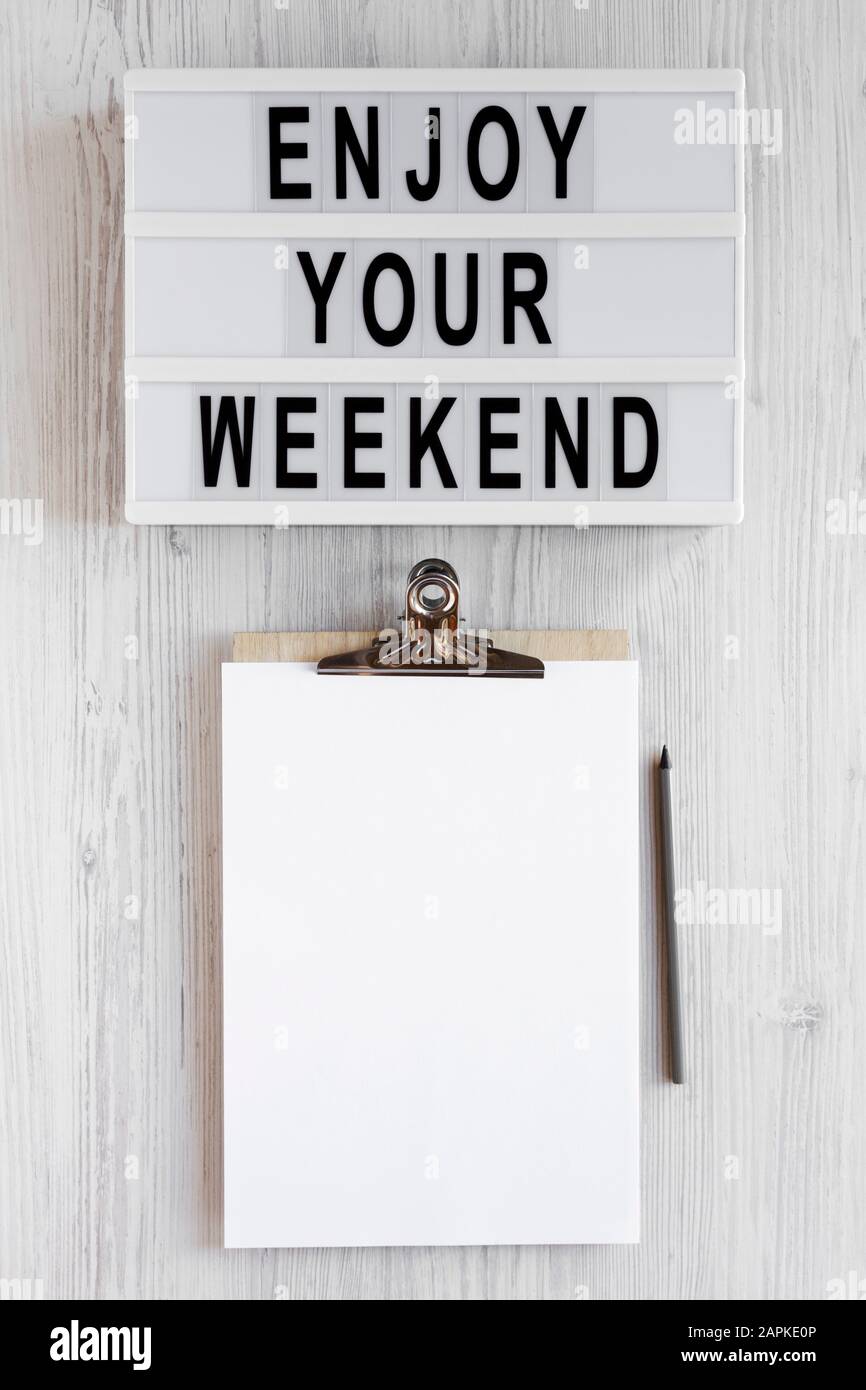 'Enjoy your weekend' words on a lightbox, clipboard with blank sheet of ...