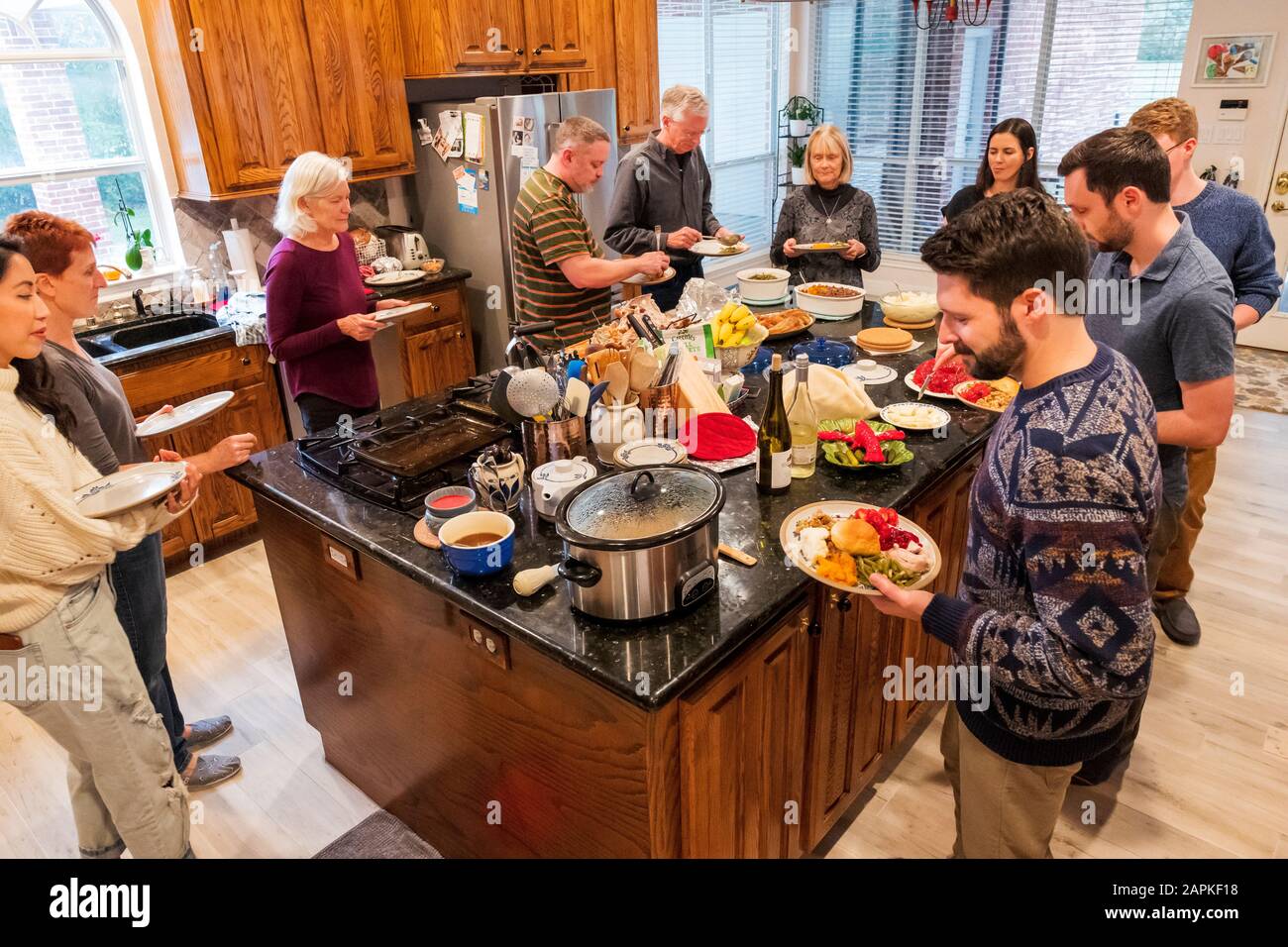Family gathered around kitchen center island for buffet style ...
