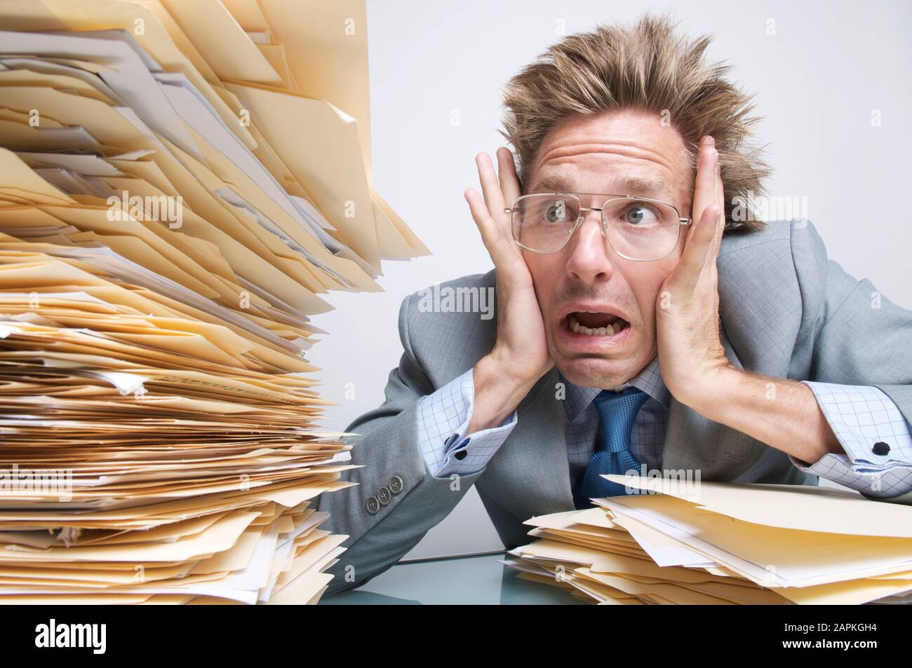 Stressed office worker looking with shock at a massive stack of file ...