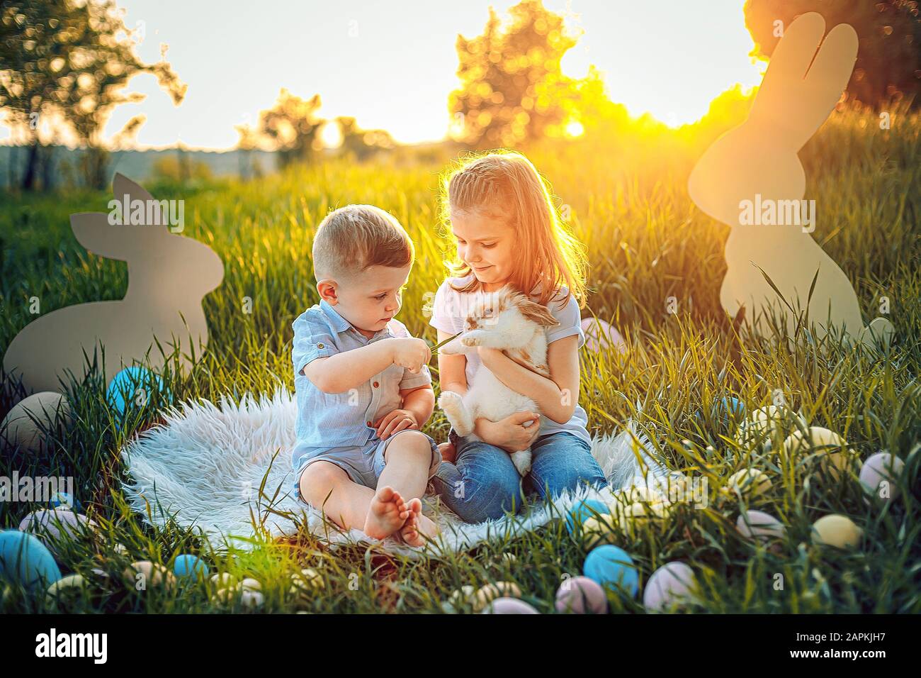 Little girl and boy play with the rabbit. happy little girl holding ...