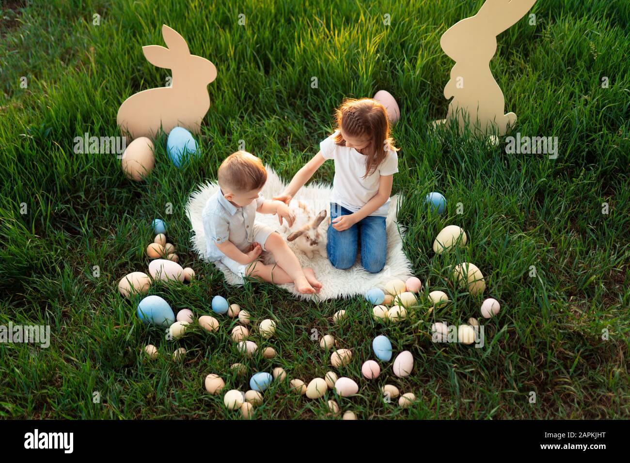 Little girl and boy play with the rabbit. happy little girl holding ...
