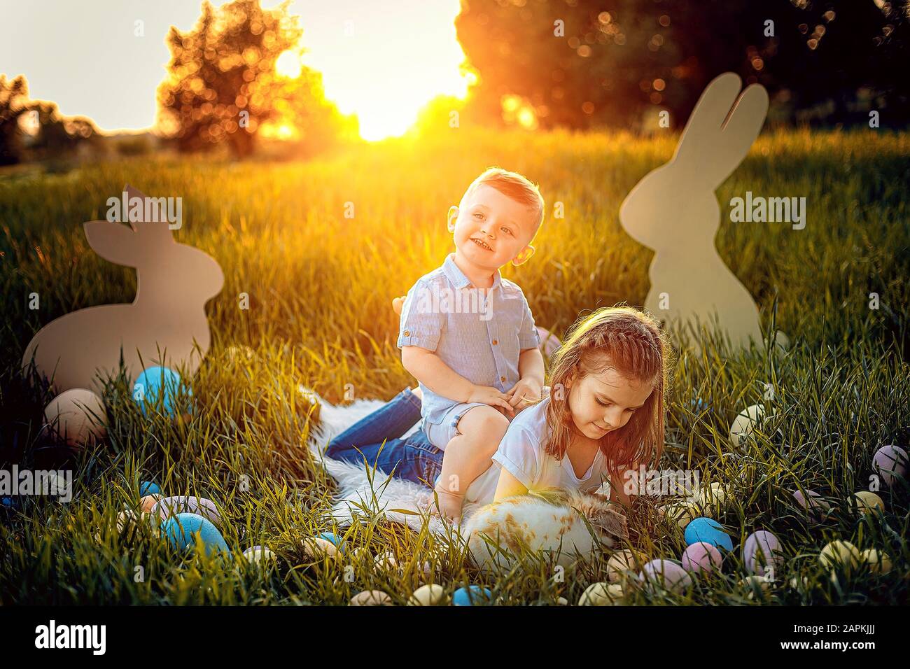 Little girl and boy play with the rabbit. happy little girl holding ...
