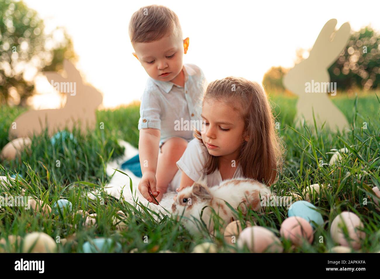 Little boy and girl play with the rabbit. happy little girl holding ...