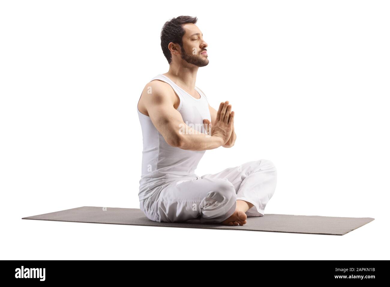 Young man sitting on an exercise mat in a meditation pose isolated on ...
