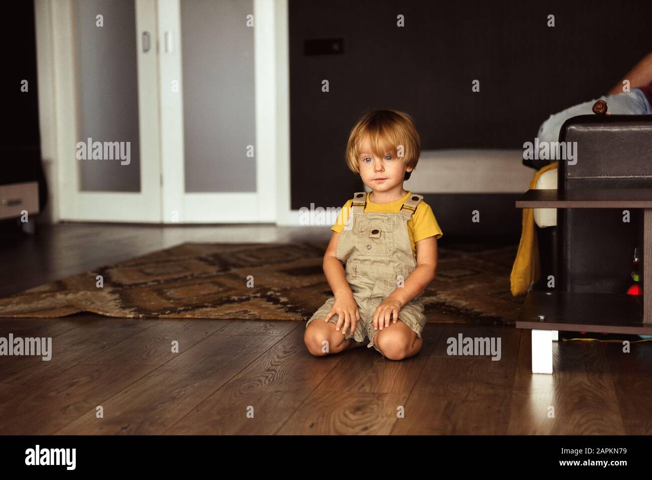 Little boy sitting on the carpet in the house Stock Photo - Alamy