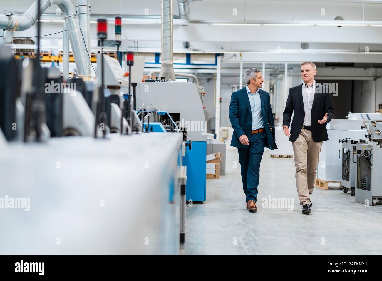Two businessmen walking and talking in a factory Stock Photo - Alamy