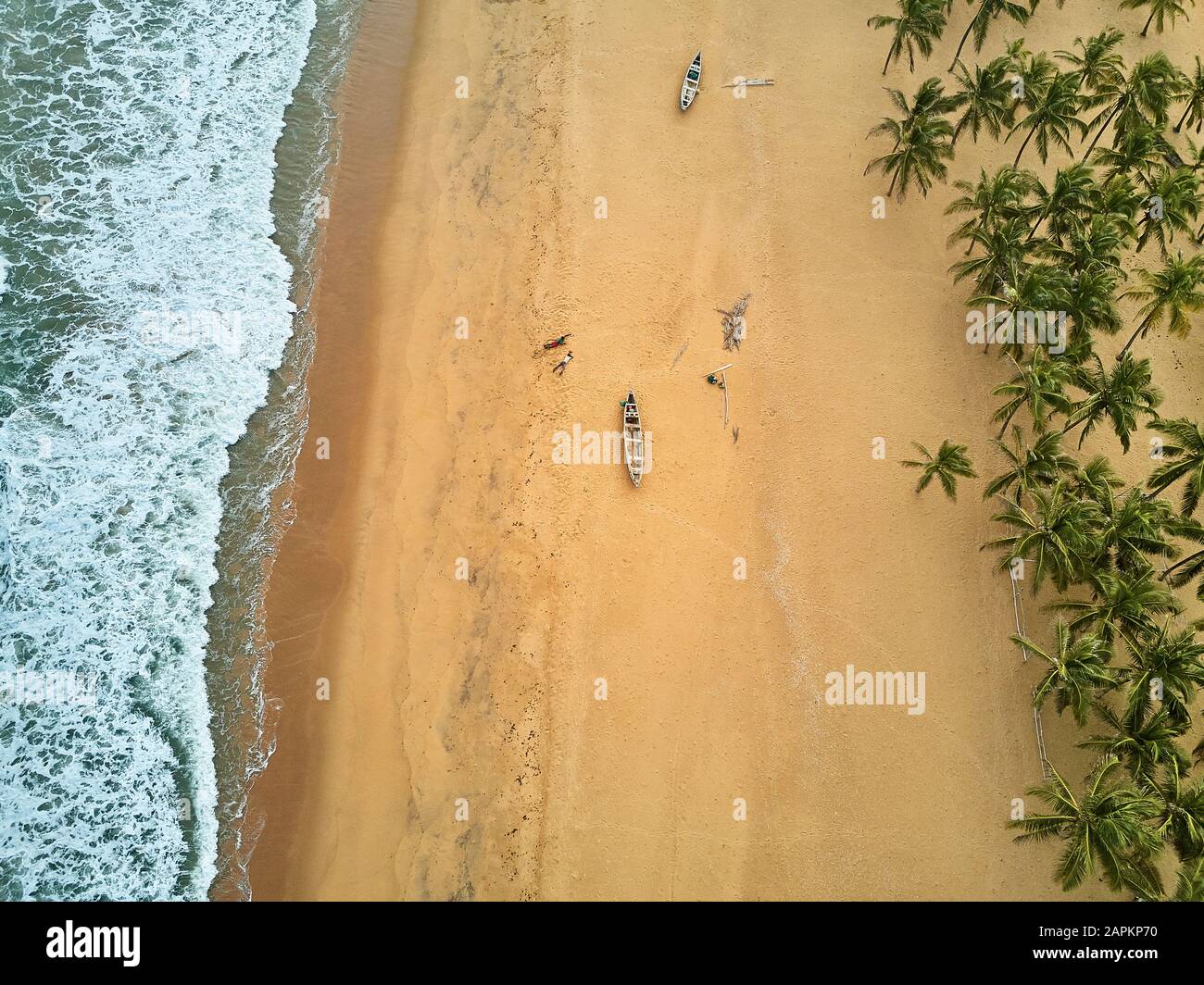 Benin, Aerial view of two fishermen relaxing on sandy coastal beach ...