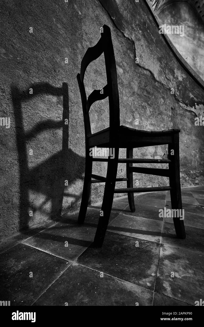 Grayscale low-angle shot of a wooden chair with a shadow on the wall ...