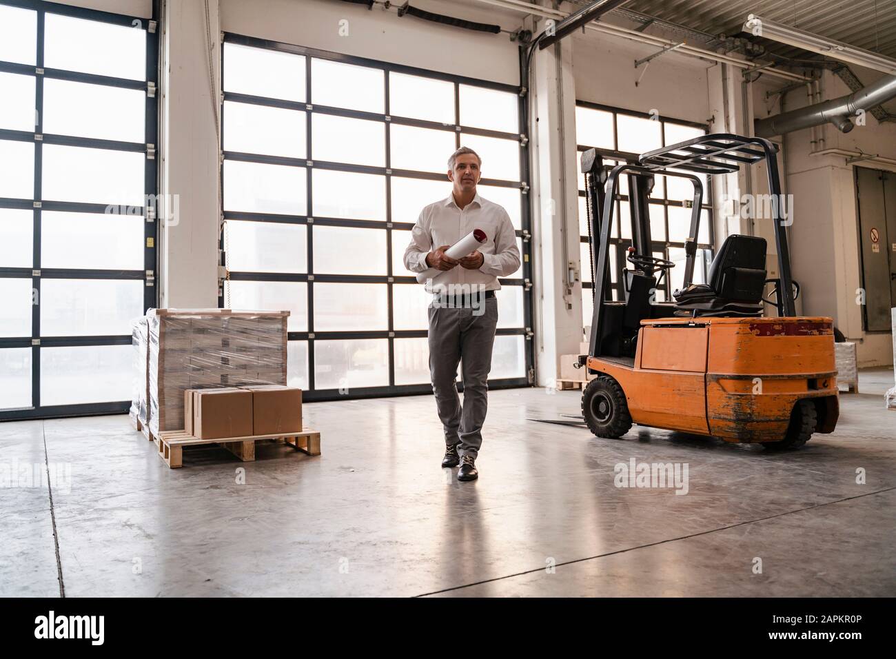 Businessman walking in a factory Stock Photo - Alamy