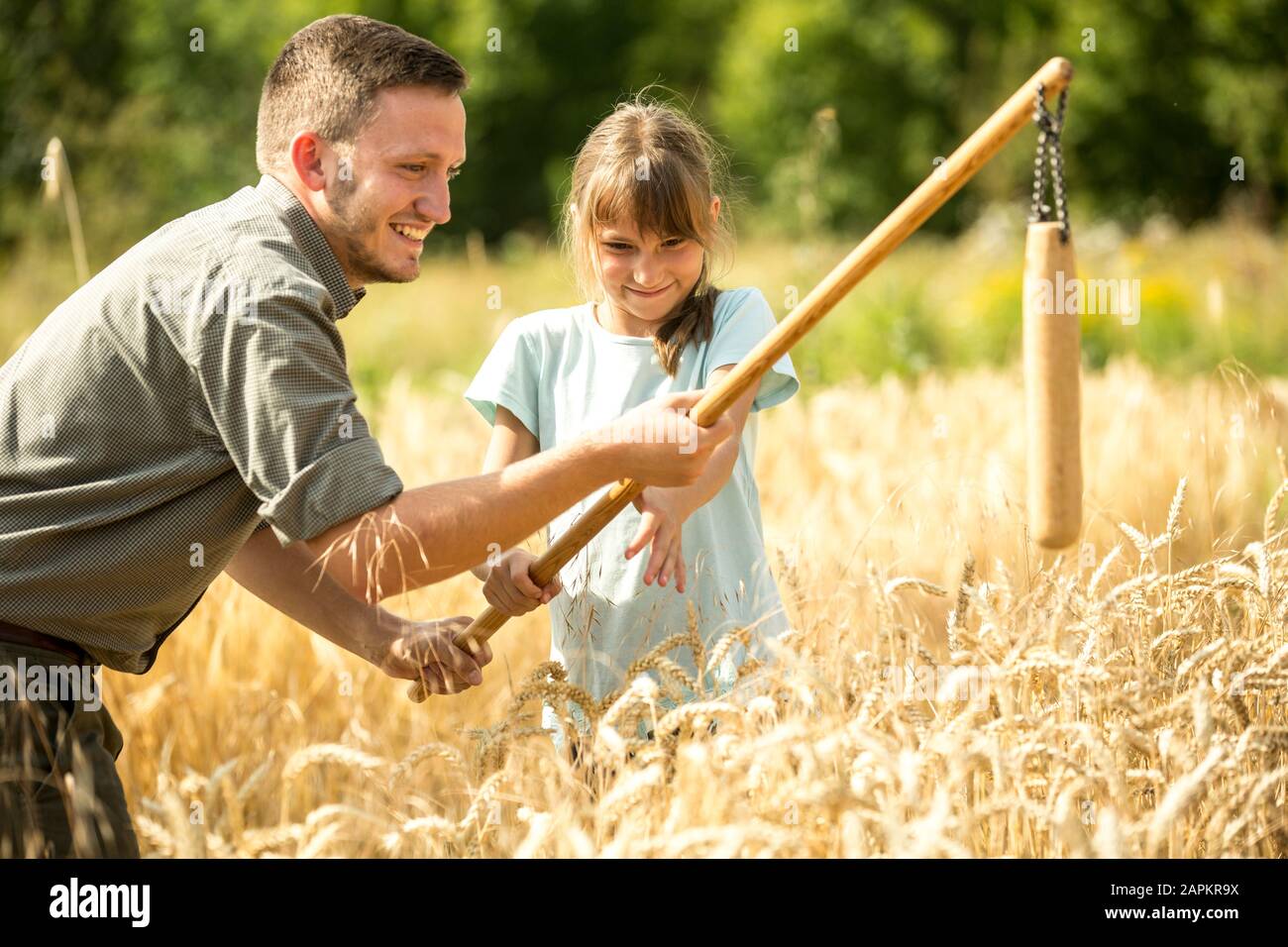 Children learning how to flail wheat in field Stock Photo - Alamy