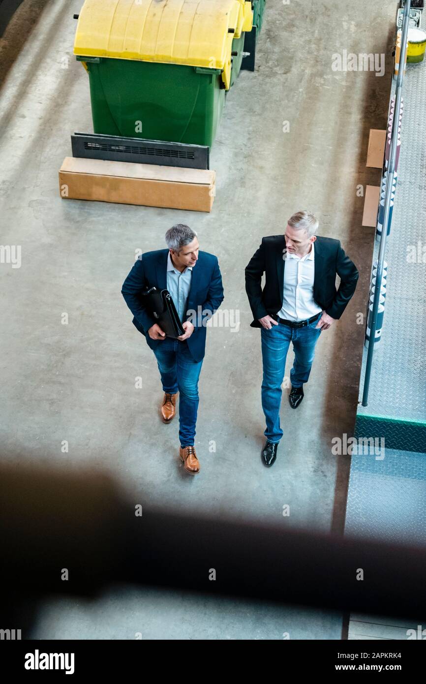 Two businessmen walking and talking in a factory Stock Photo - Alamy