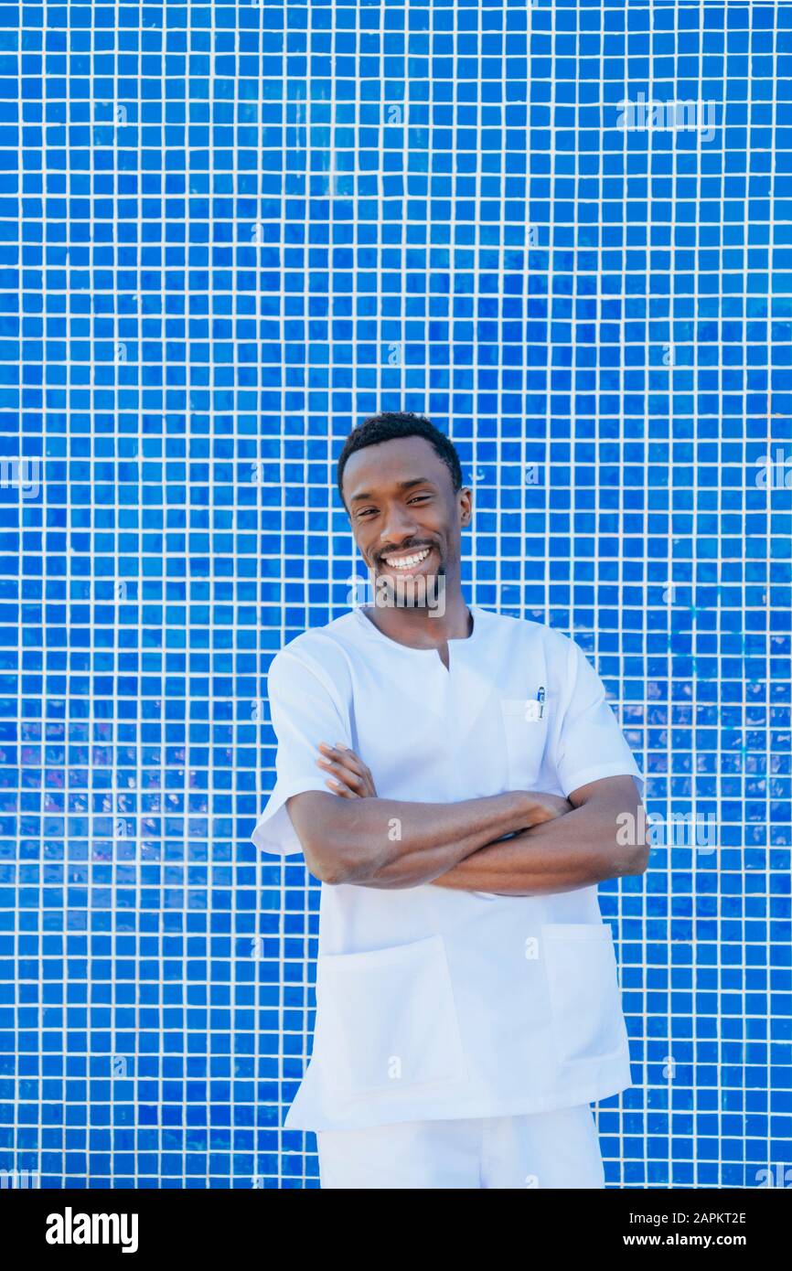 Portrait of laughing doctor standing against blue tiled wall Stock ...