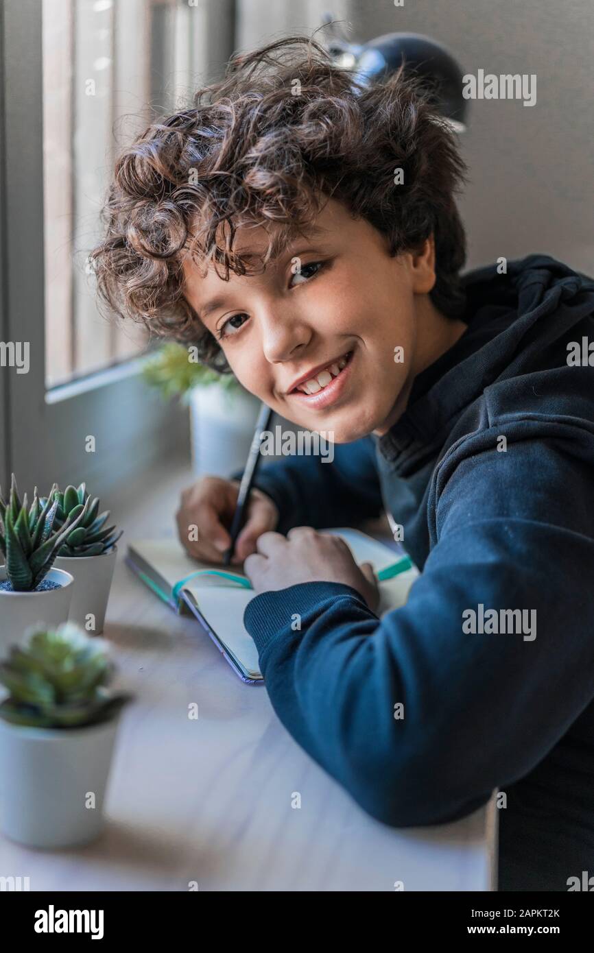 Portrait of smiling boy taking notes at the window Stock Photo - Alamy