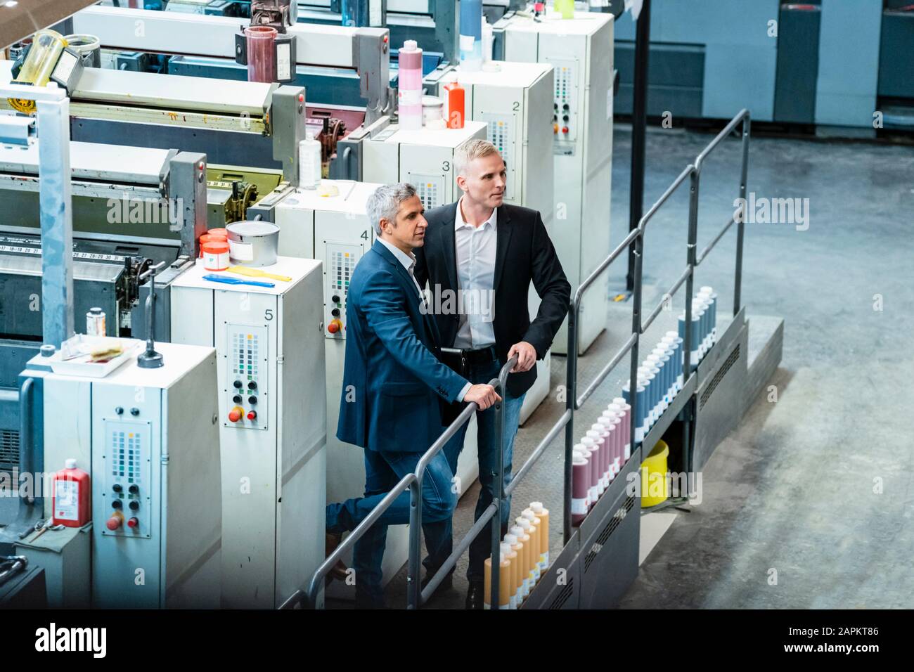 Two businessmen in a printing shop looking around Stock Photo - Alamy