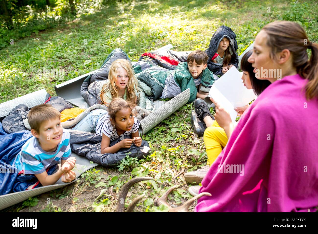 Teacher reading story to school children, camping in the forest Stock ...