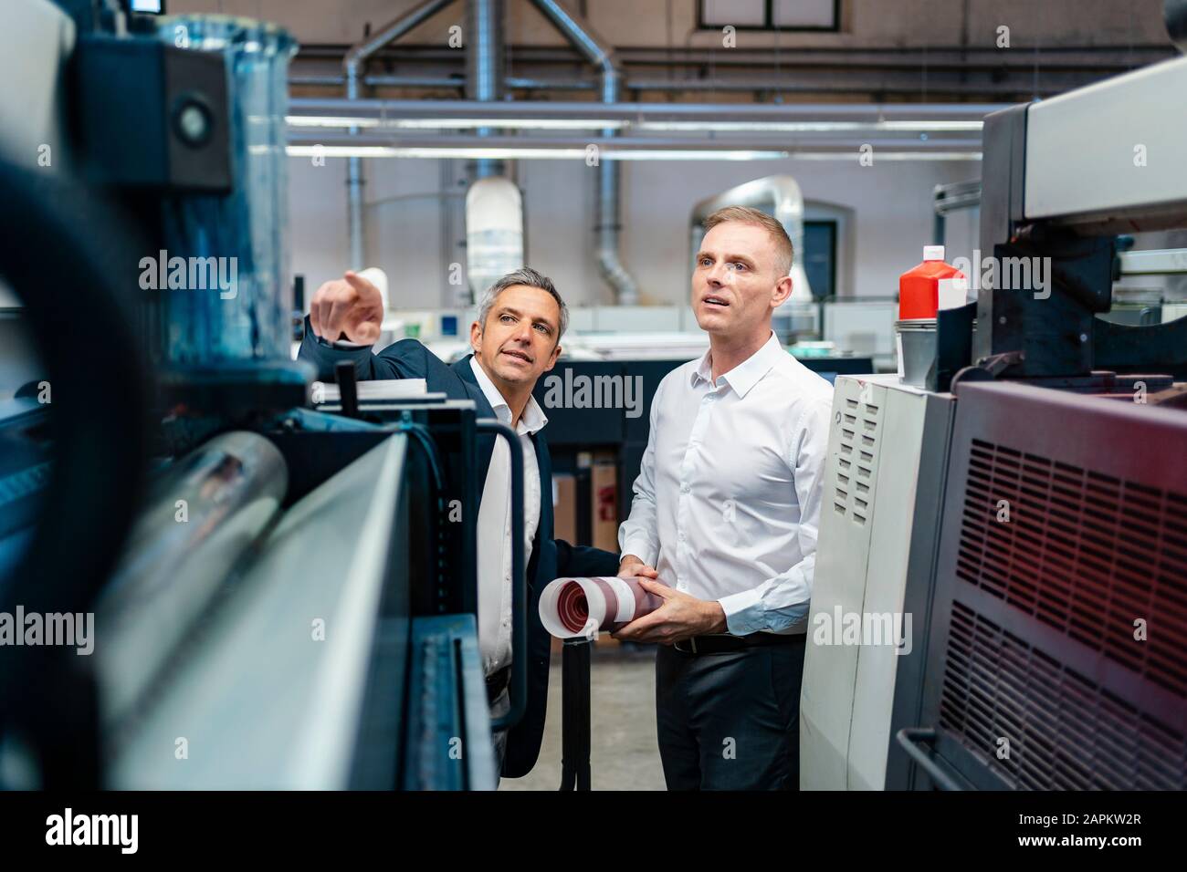 Two businessmen talking in a factory Stock Photo - Alamy