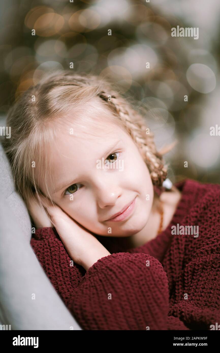 Portrait of blond little girl wearing ruby knit pullover at home Stock ...
