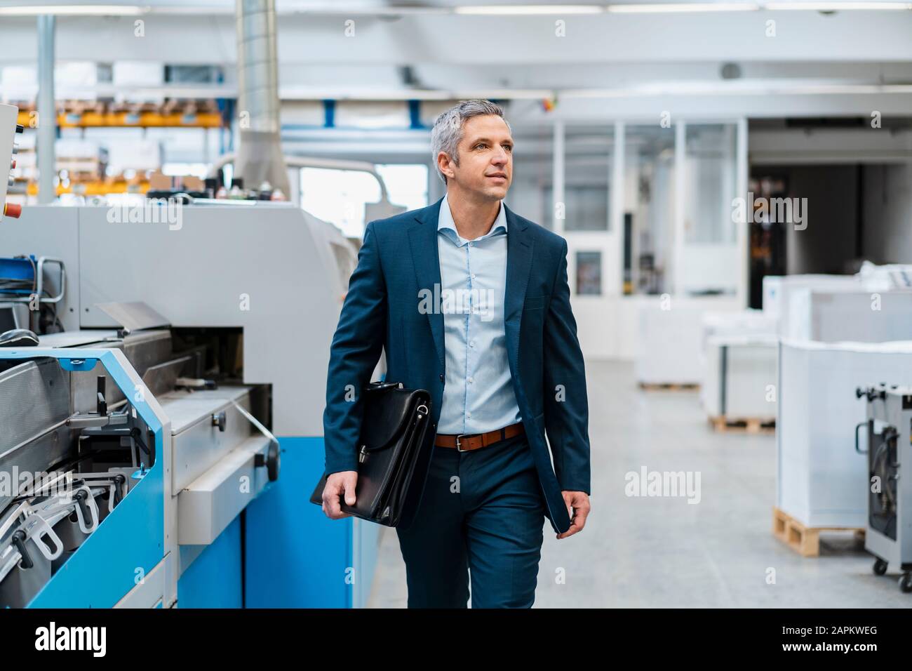 Businessman walking in a factory Stock Photo - Alamy