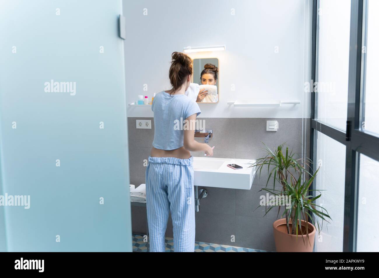 Rear view of young woman brushing teeth in bath room Stock Photo - Alamy