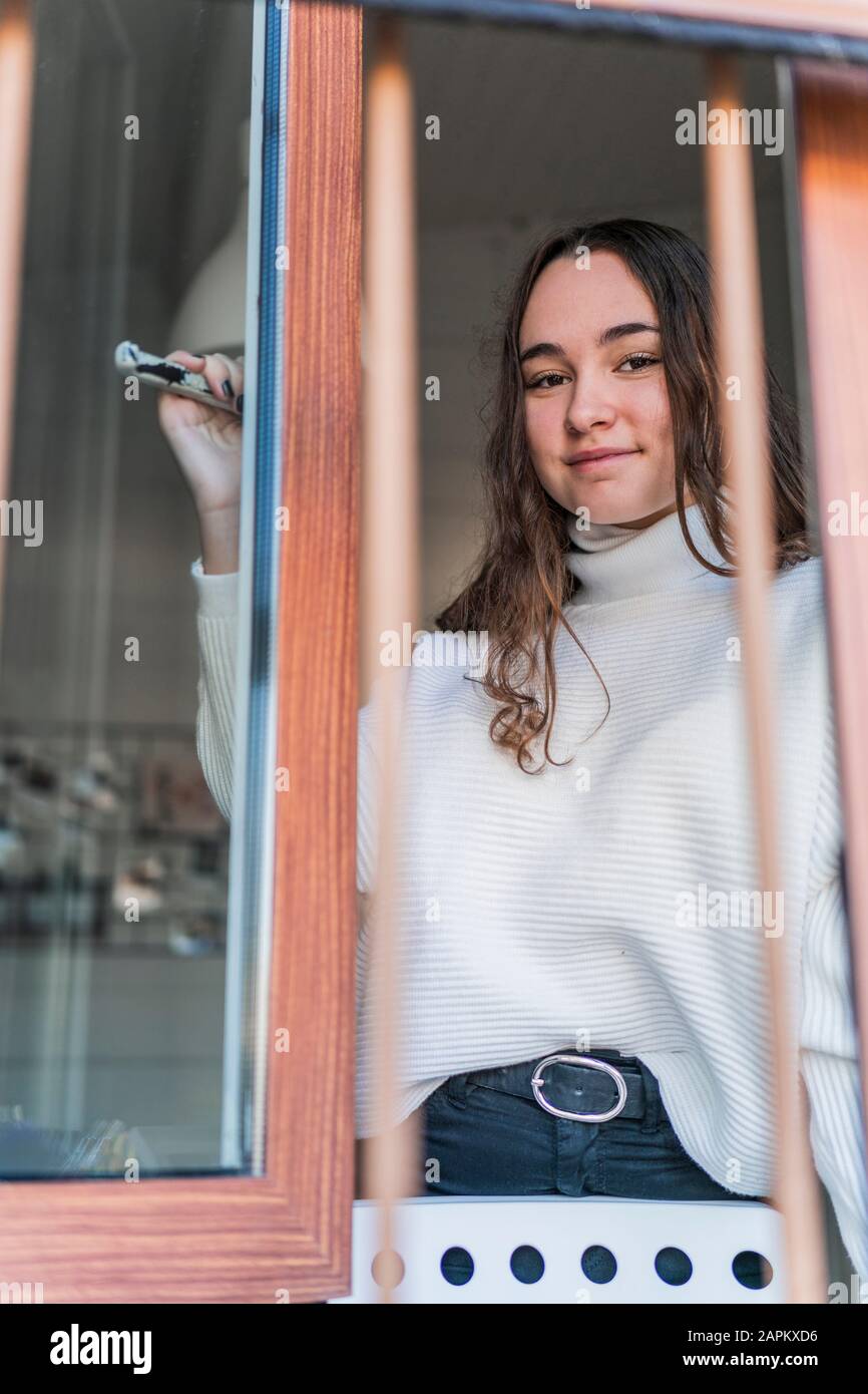 Portrait of smiling teenage girl looking out of window Stock Photo - Alamy