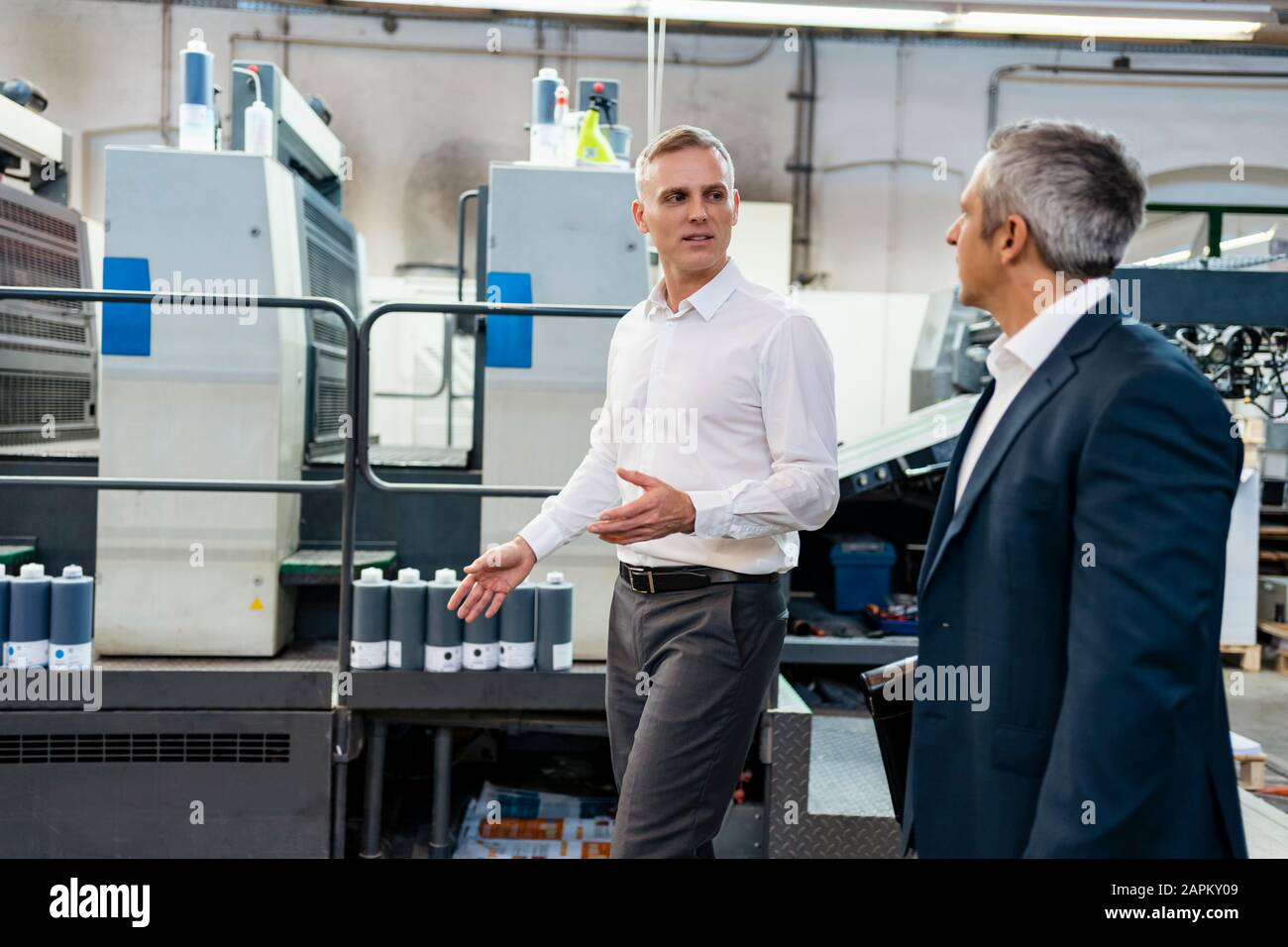 Two businessmen talking in a factory Stock Photo - Alamy