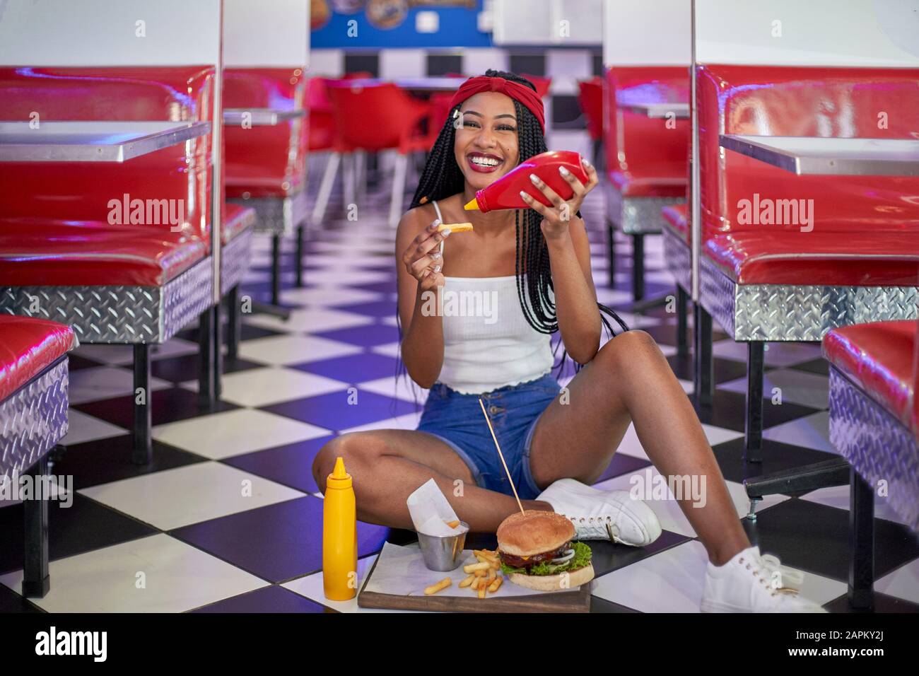 Young woman with braided hairstyle putting tomato sauce on a chip Stock ...