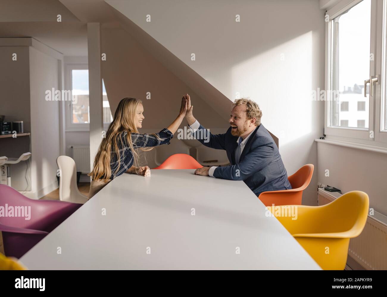 Businessman and businesswoman high fiving in office Stock Photo - Alamy