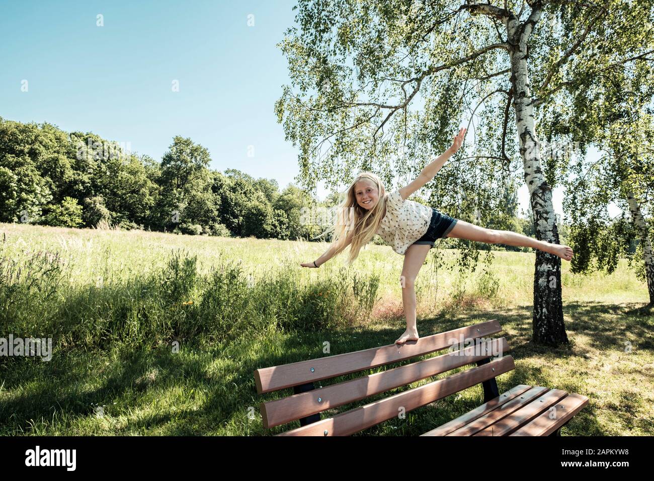 Girl balancing on a bench in park Stock Photo - Alamy