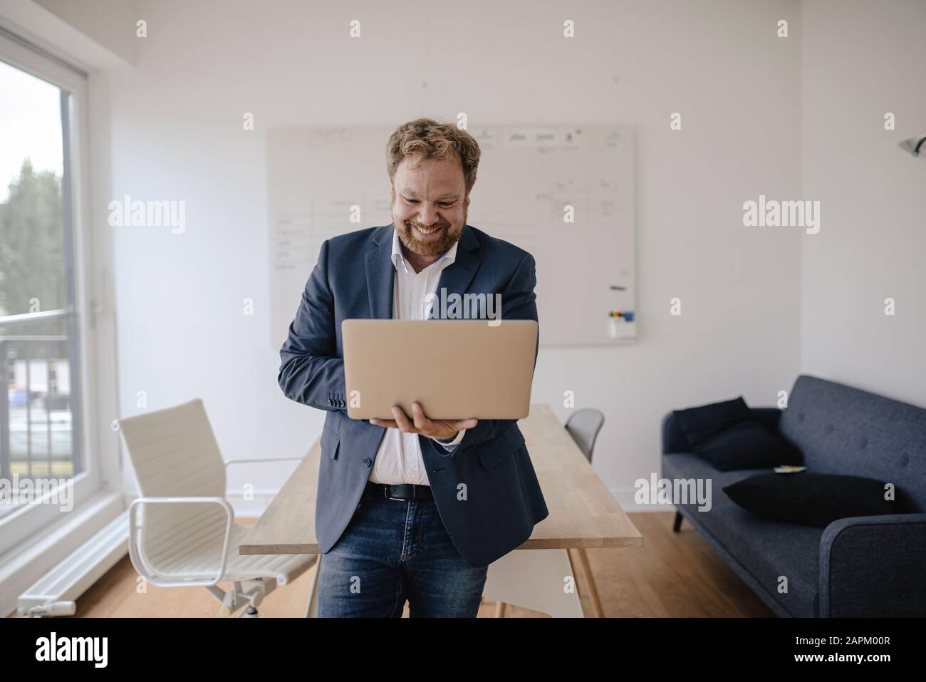Smiling businessman using laptop in office Stock Photo - Alamy