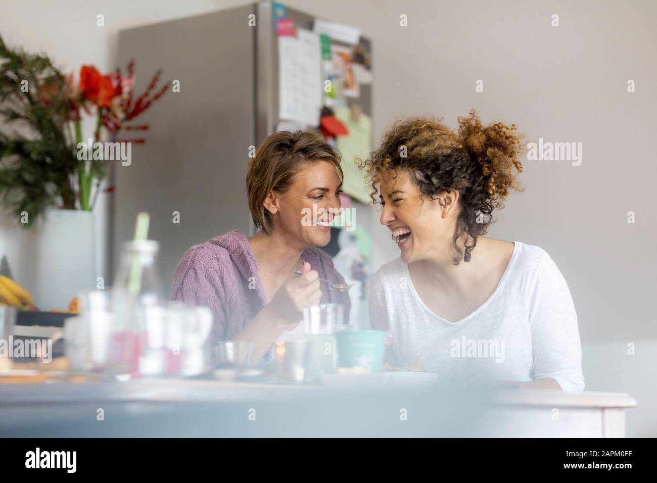 Two happy women sitting and talking at kitchen table at home Stock ...