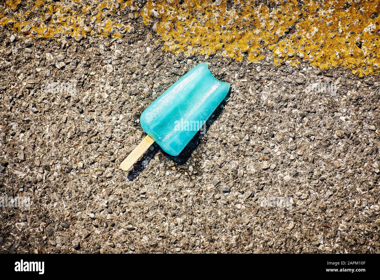 Bitten light blue popsicle on asphalt Stock Photo - Alamy