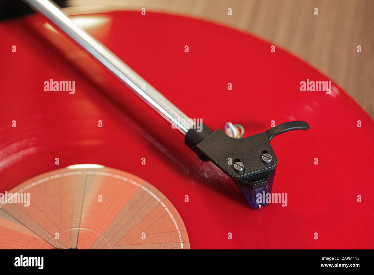 Closeup shot of a modern gramophone with a red disc and headshell in a ...